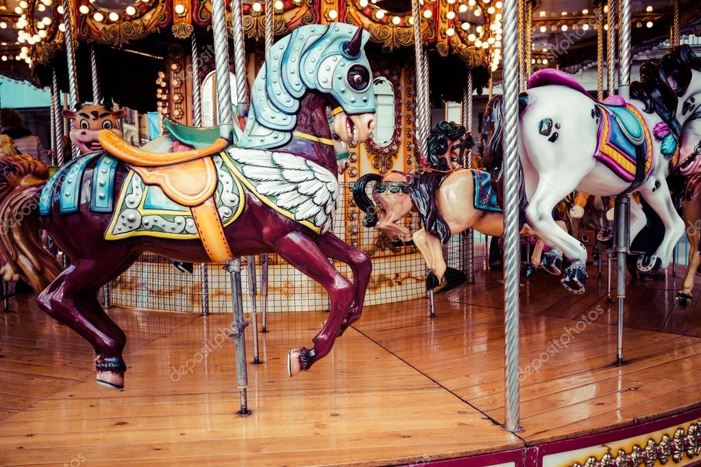 Old French carousel in a holiday park. Three horses and airplane on a ...