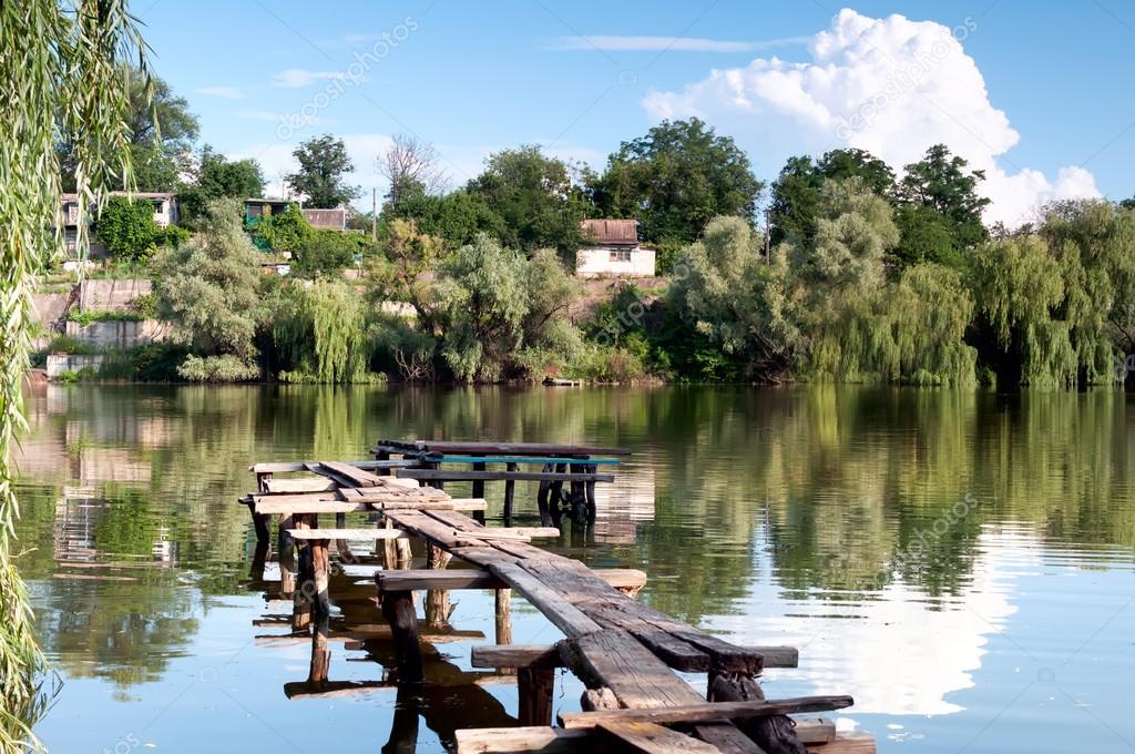 Vista sobre el río con edificios rurales y puente de madera 2023