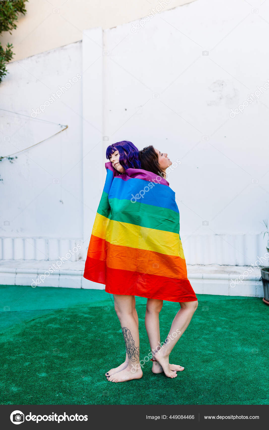 Two women with rainbow flag on a backyard. Couple Young lesbian girls ...