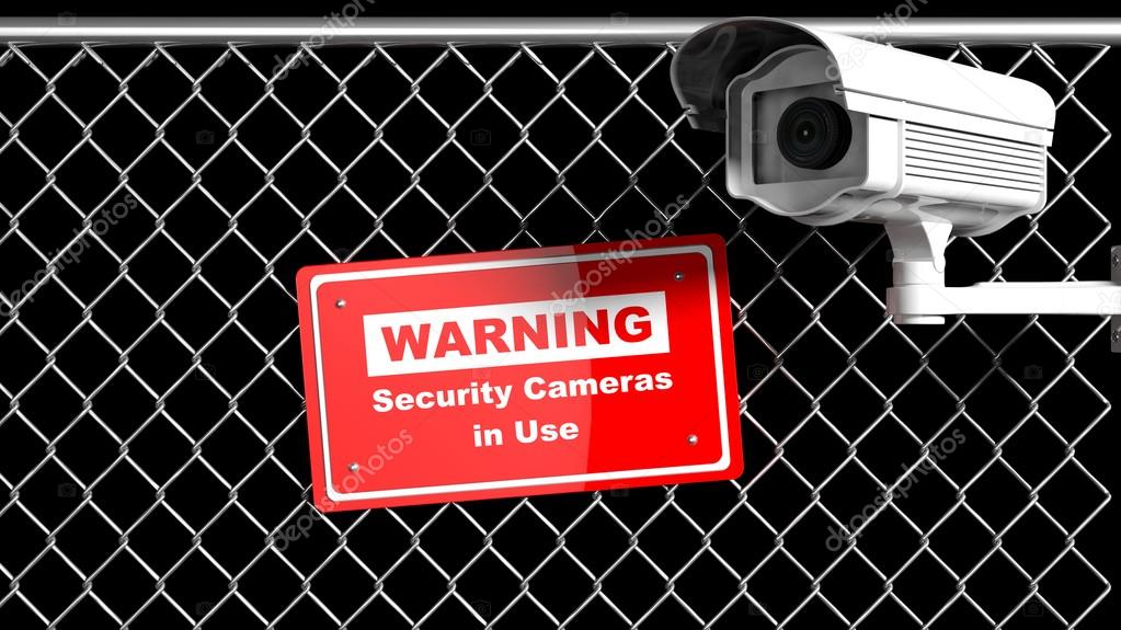 Security surveillance camera on chain-link fence with warning sign on ...