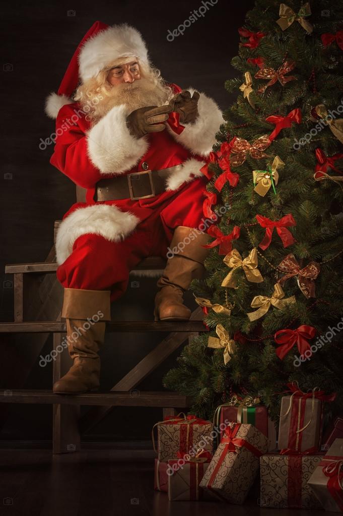 Santa Claus decorating Christmas tree Stock Photo by ©HASLOO 53761165