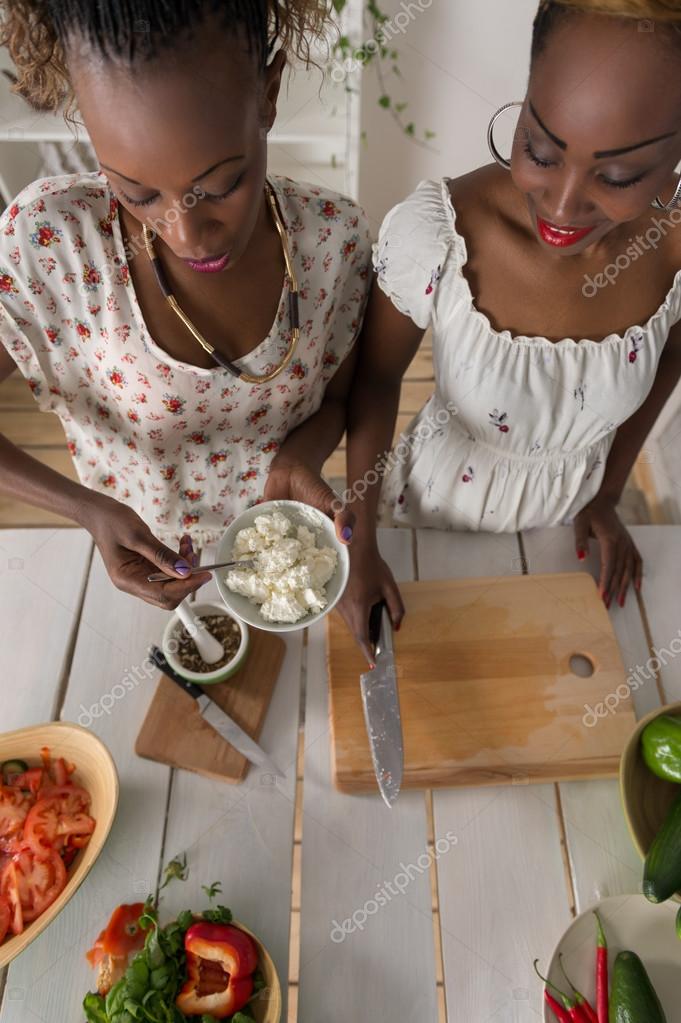 Two african women cooking salad Stock Photo by ©HASLOO 65007943