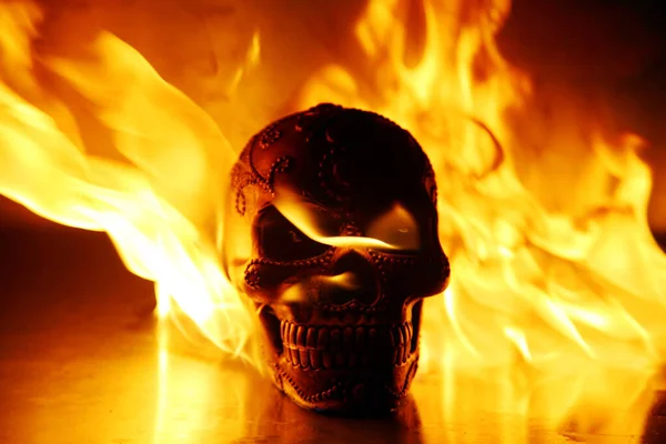 Skeleton in flames sitting on a wooden stool laughing in a burning ...