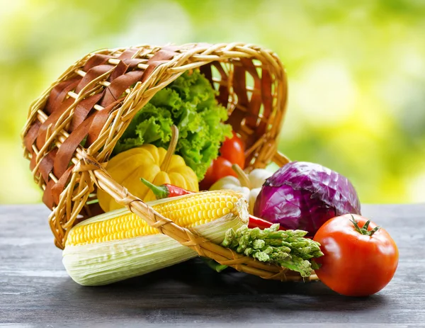 Fresh vegetables falling out of an inverted basket on black wood ...