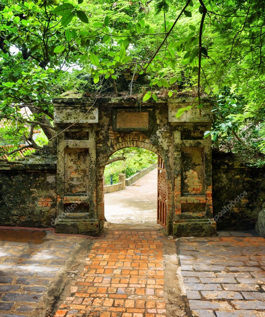 Brick walkway to old stone gate leading into tropical garden — Stock ...