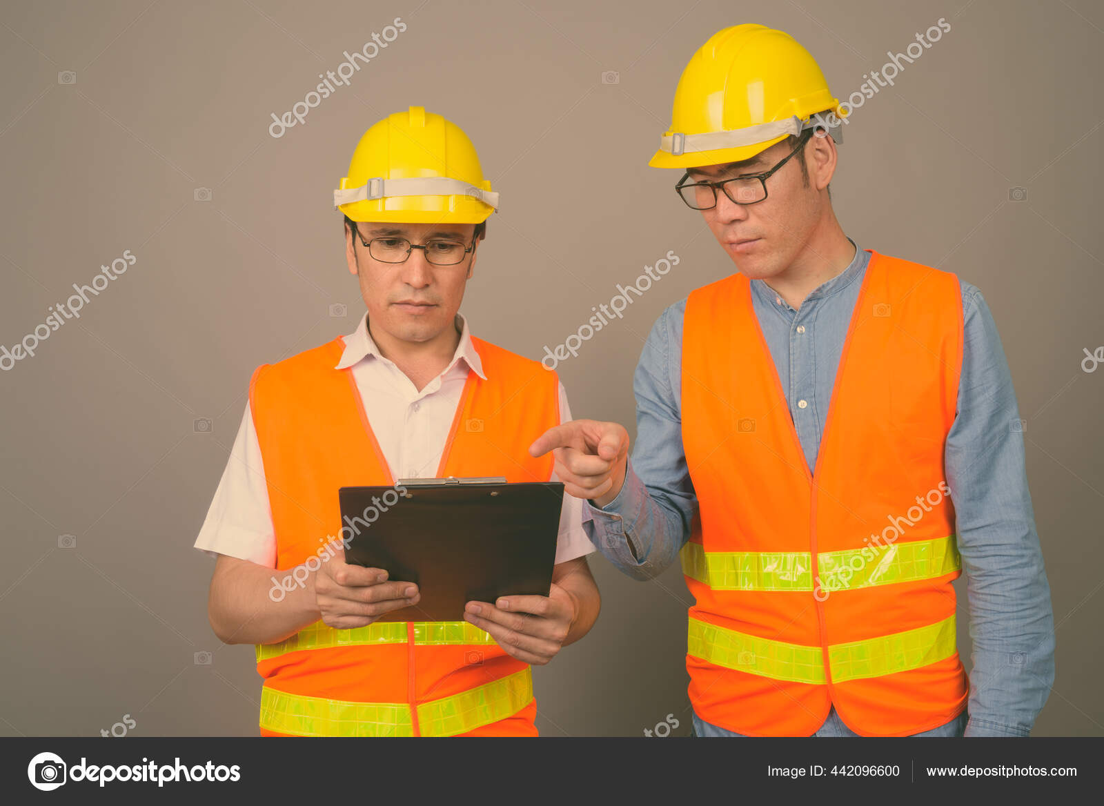 Two young Asian men construction worker together against gray ...