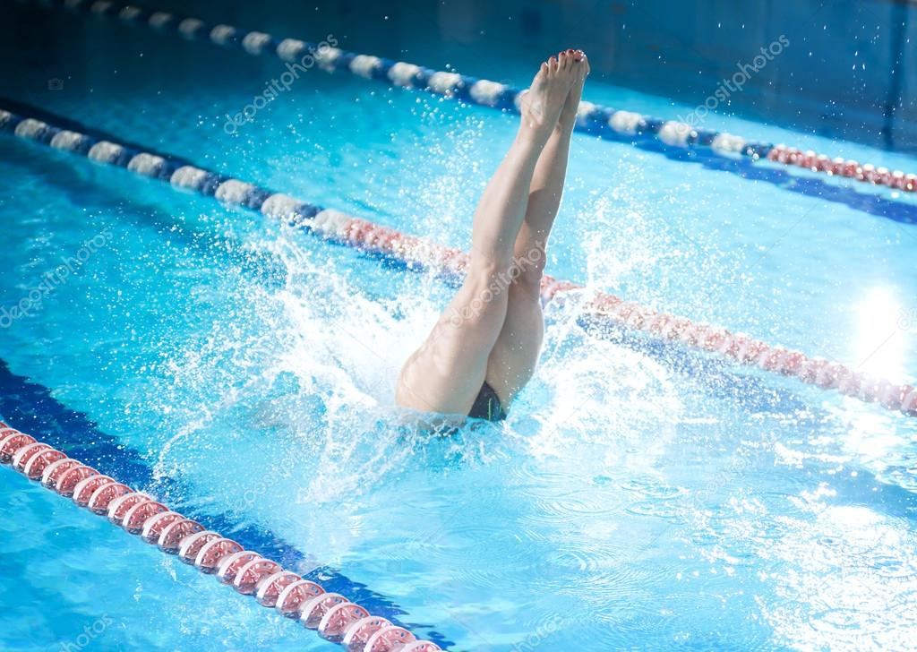Female swimmer jumping into swimming pool. Stock Photo by ©markin 52924319