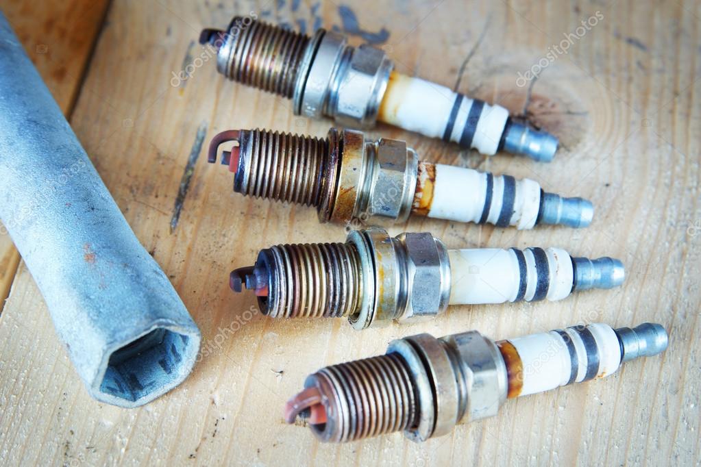 Spare parts. Spark plugs lie on the wooden workbench in a garage Stock ...