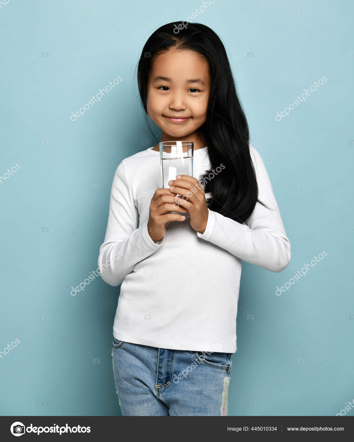 Cute smiling asian Korean kid girl in jeans and white long sleeve shirt ...