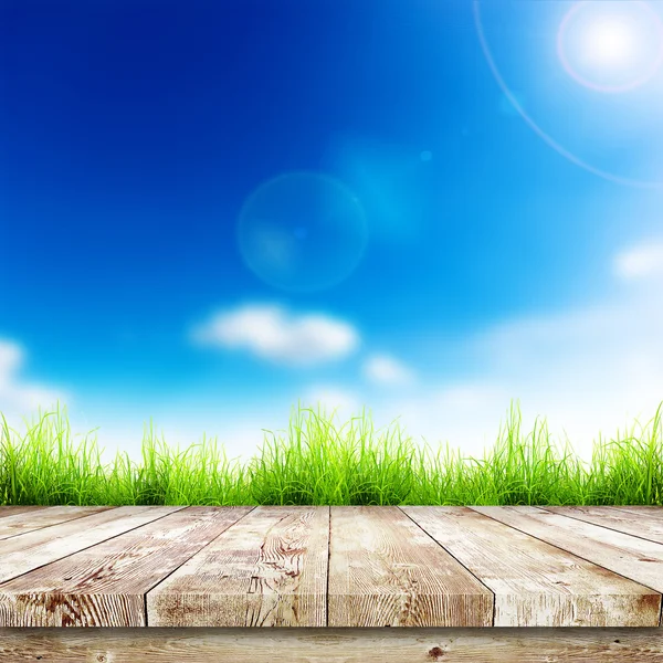 Green grass on wooden plank over a blue sky with hearts shape clouds ...