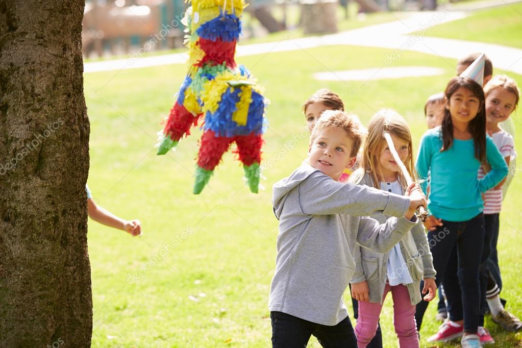 Children Hitting Pinata At Birthday Party Stock Photo by ...