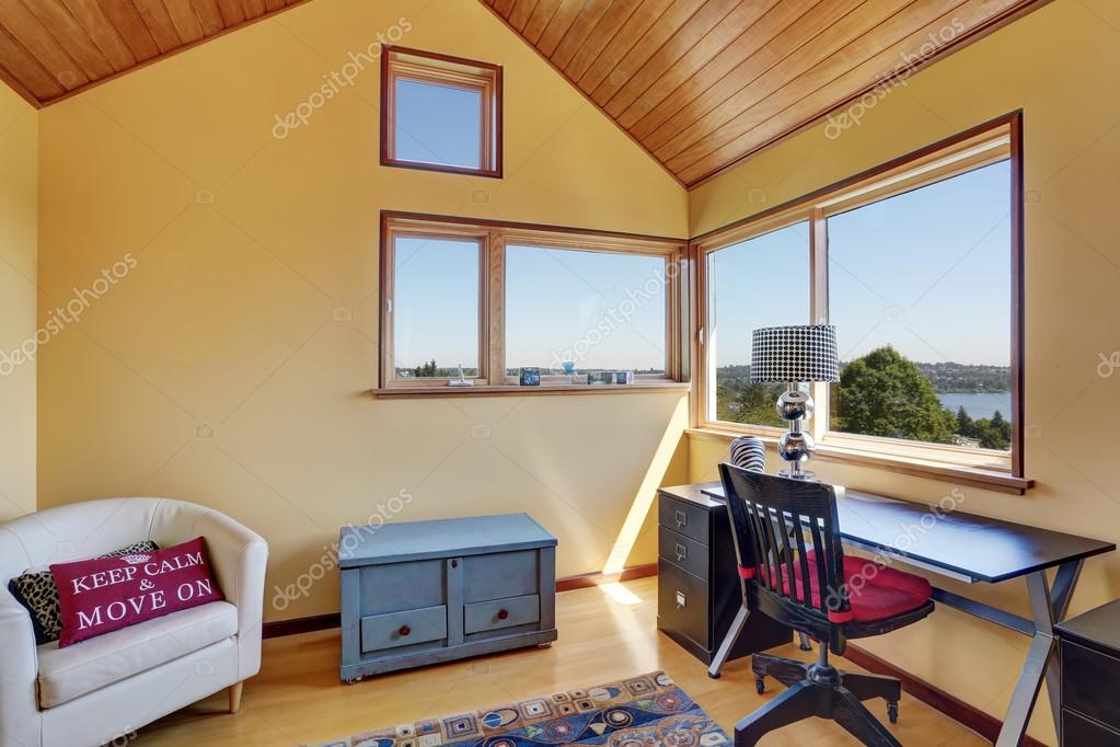 Vaulted ceiling home office interior with black desk and window view ...