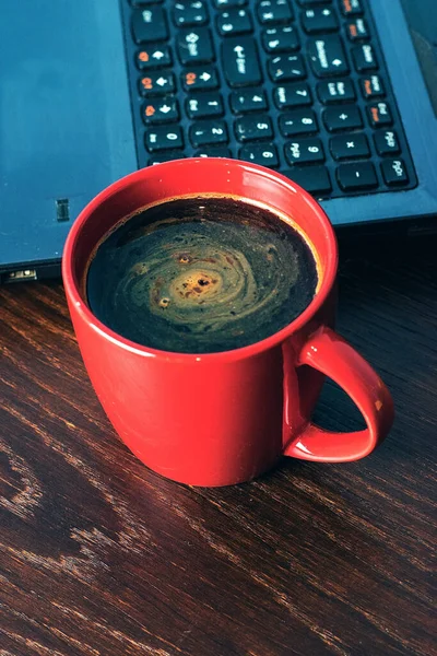 Cup of coffee and laptop on the background on a brown wooden table ...