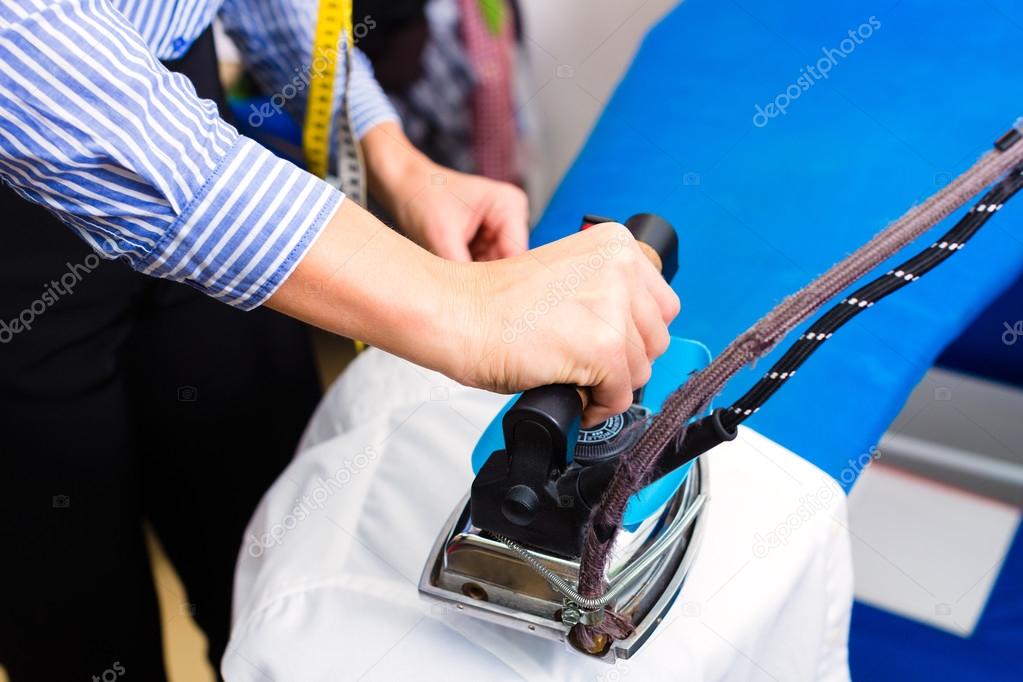 Cleaner in laundry shop ironing jacket — Stock Photo © Kzenon #79393612