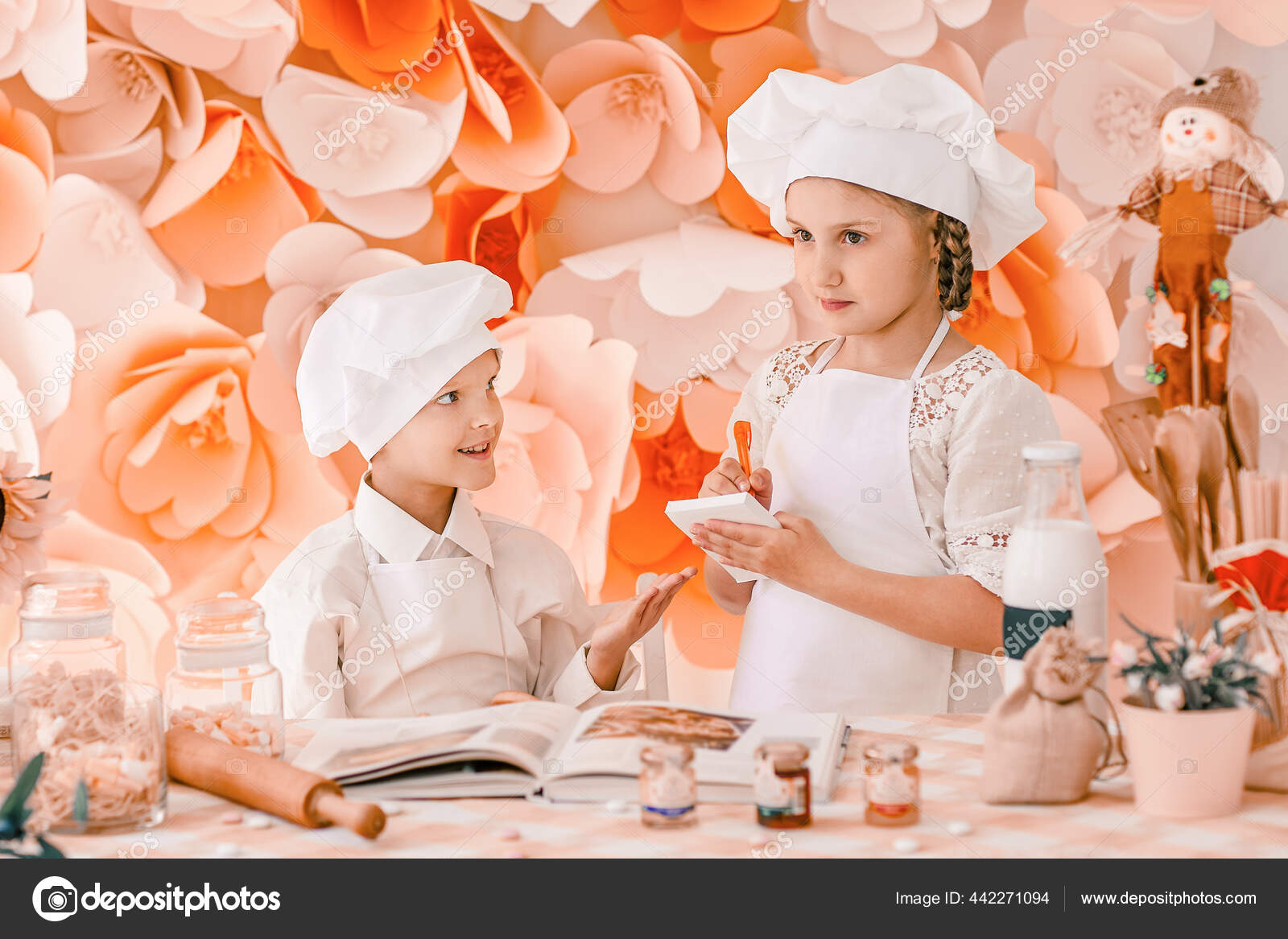 Brother and sister in uniform chefs record menu standing at the kitchen ...