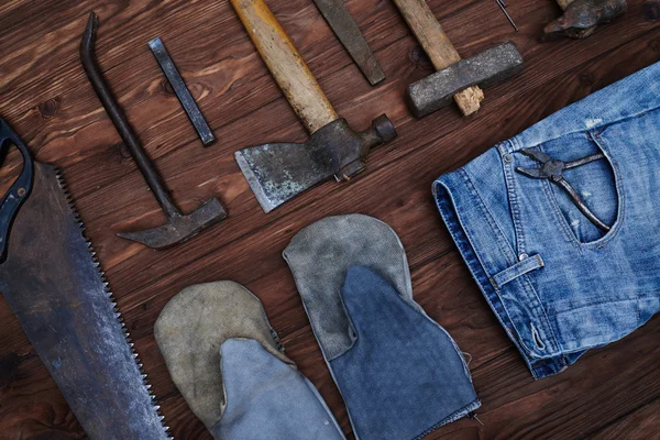 Top view of worn tools kit and denim jeans with gloves over wood ...