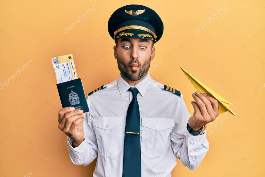 Hombre piloto hispano guapo sosteniendo avión de papel y pasaporte ...