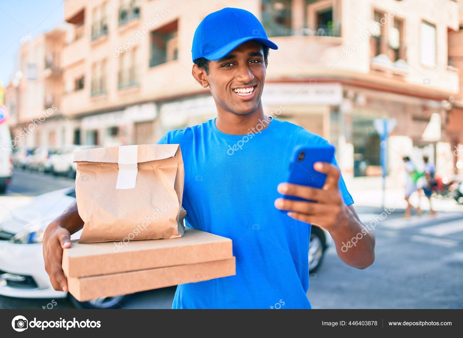 African Delivery Man Wearing Courier Uniform Outdoors Using Smartphone ...