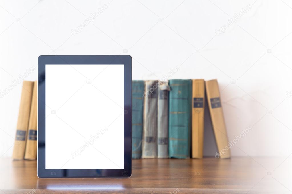 Stack of old books and tablet over wooden table, retro filtered image ...