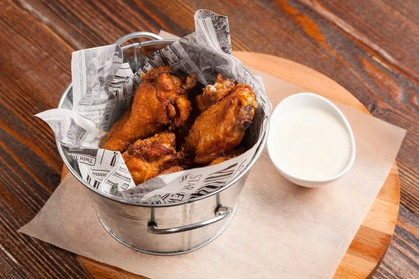 chicken wings in a bucket on wooden table - Stock Image - Everypixel