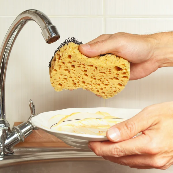 Hands with sponge and dirty dishes over the sink in kitchen - Stock ...