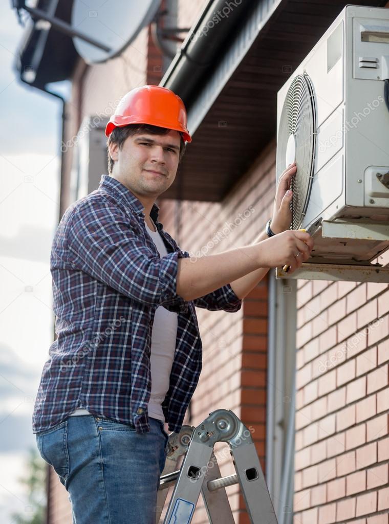 Young engineer installing air conditioner on building outer wall Stock ...