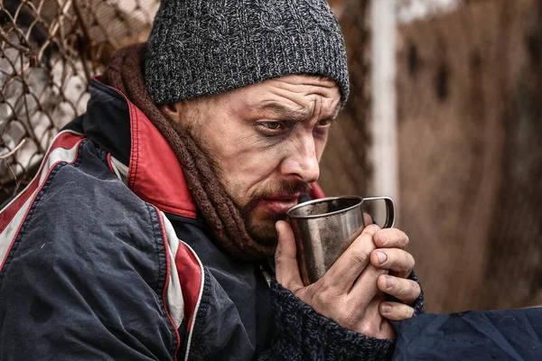 Poor homeless man with cup of hot drink outdoors on winter day - Stock ...