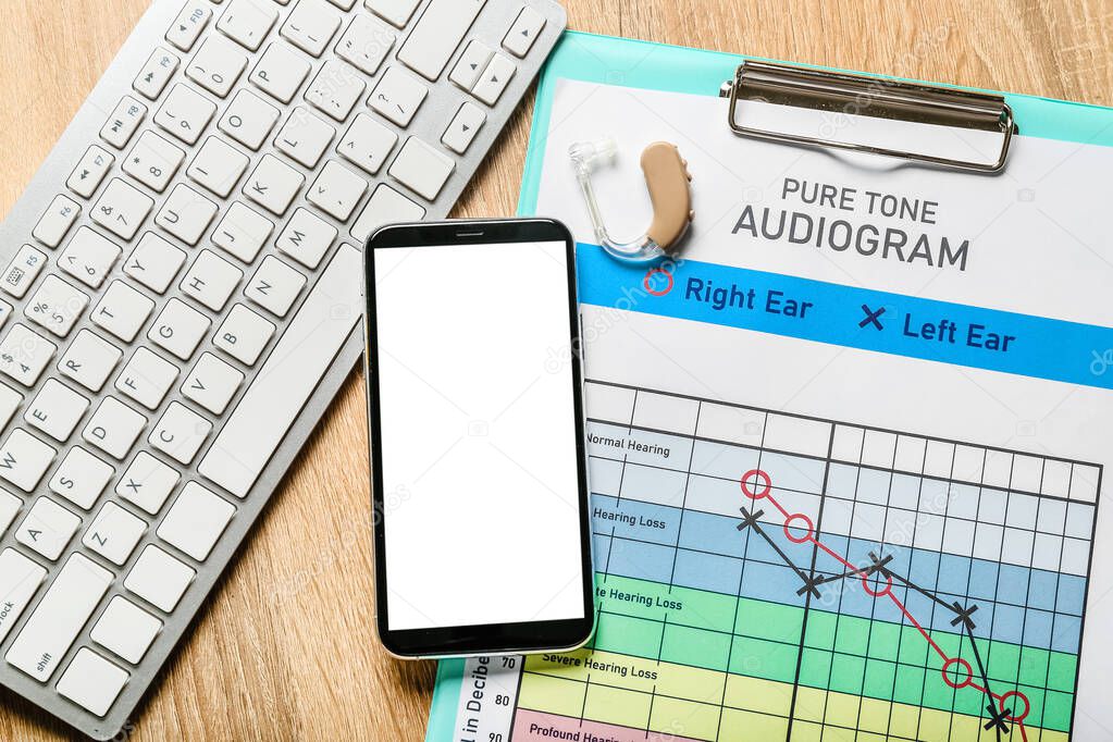 Audiograma con aud fonos y aparatos sobre fondo de madera 2024