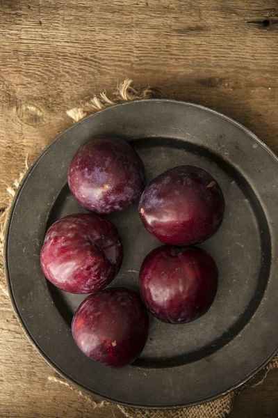 Fresh plums in natural light setting with moody vintage retro st ...