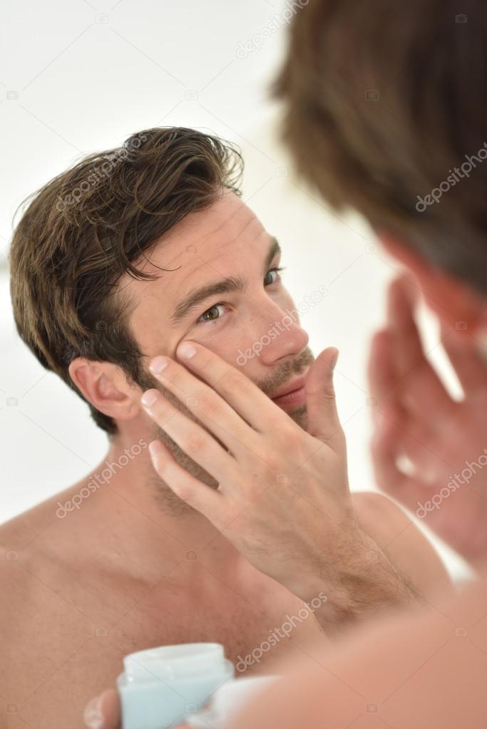 Man applying facial cream Stock Photo by ©Goodluz 100576694