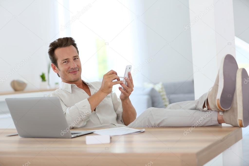 Relaxed man using smartphone Stock Photo by ©Goodluz 53347225