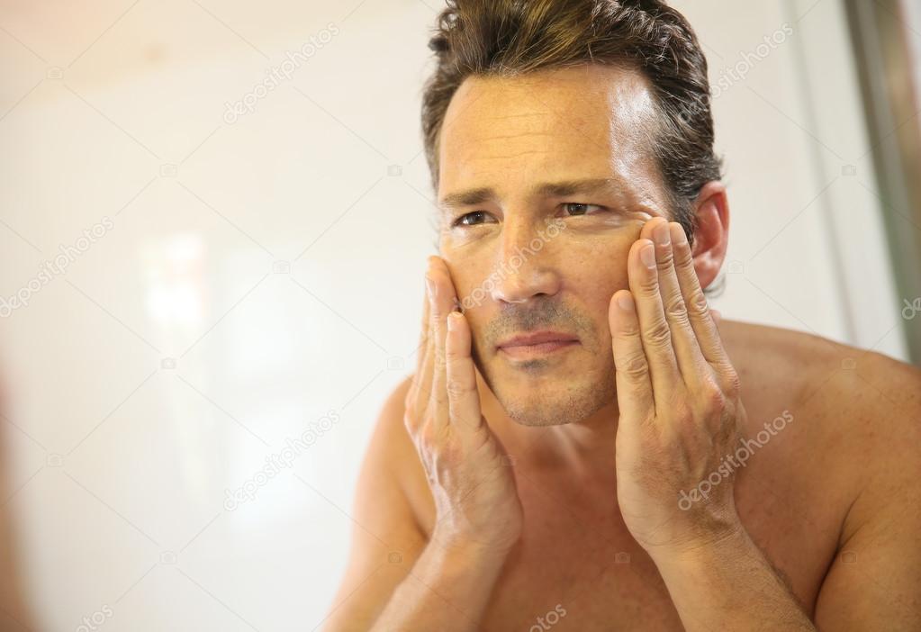 Man applying facial lotion Stock Photo by ©Goodluz 64679347