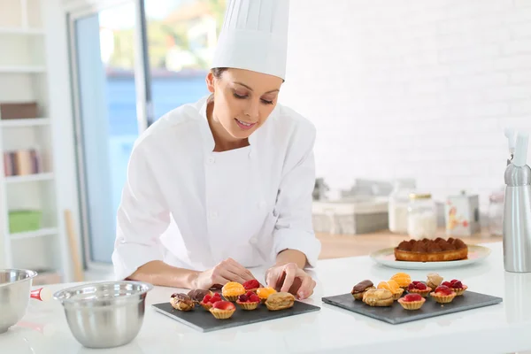 Pastry-cook preparing plate of cake bites - Stock Image - Everypixel