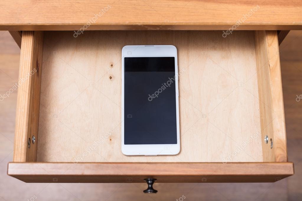 Mobile phone in open drawer Stock Photo by ©vvoennyy 120575472