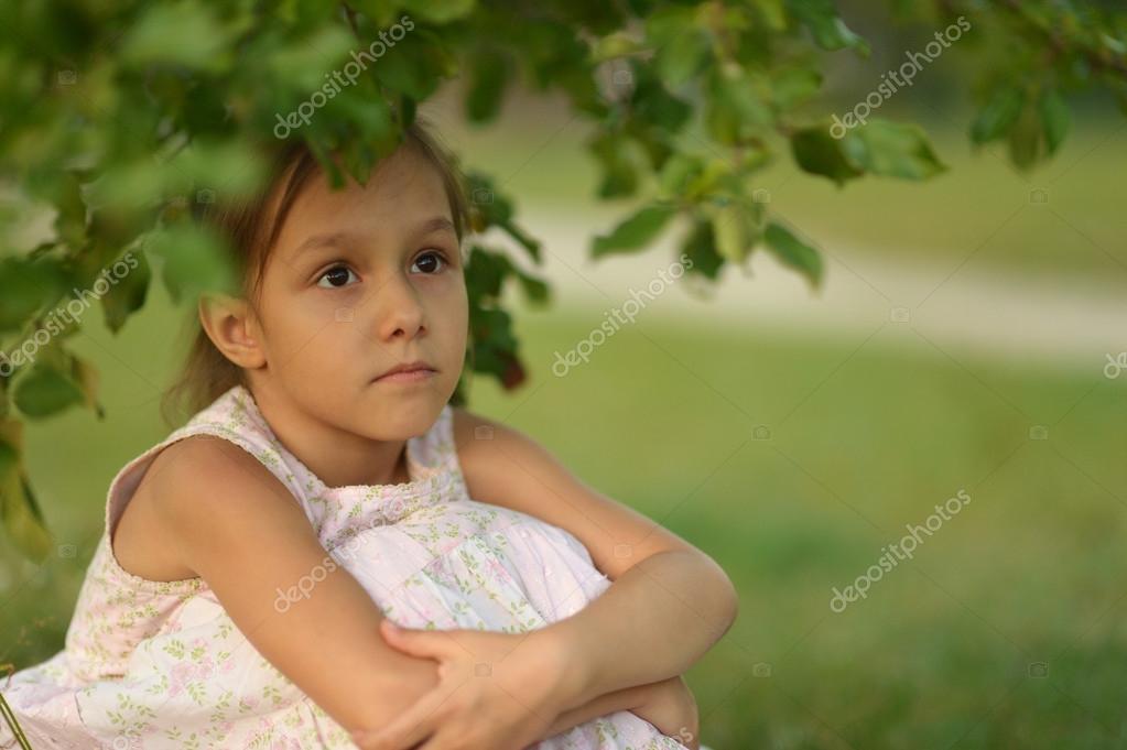 Little girl sitting under tree Stock Photo by ©aletia 68923527