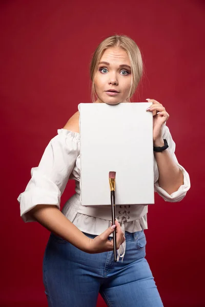 Rubia artista mostrando su obra de arte con vacilación y busca críticas. Foto de alta calidad 2023