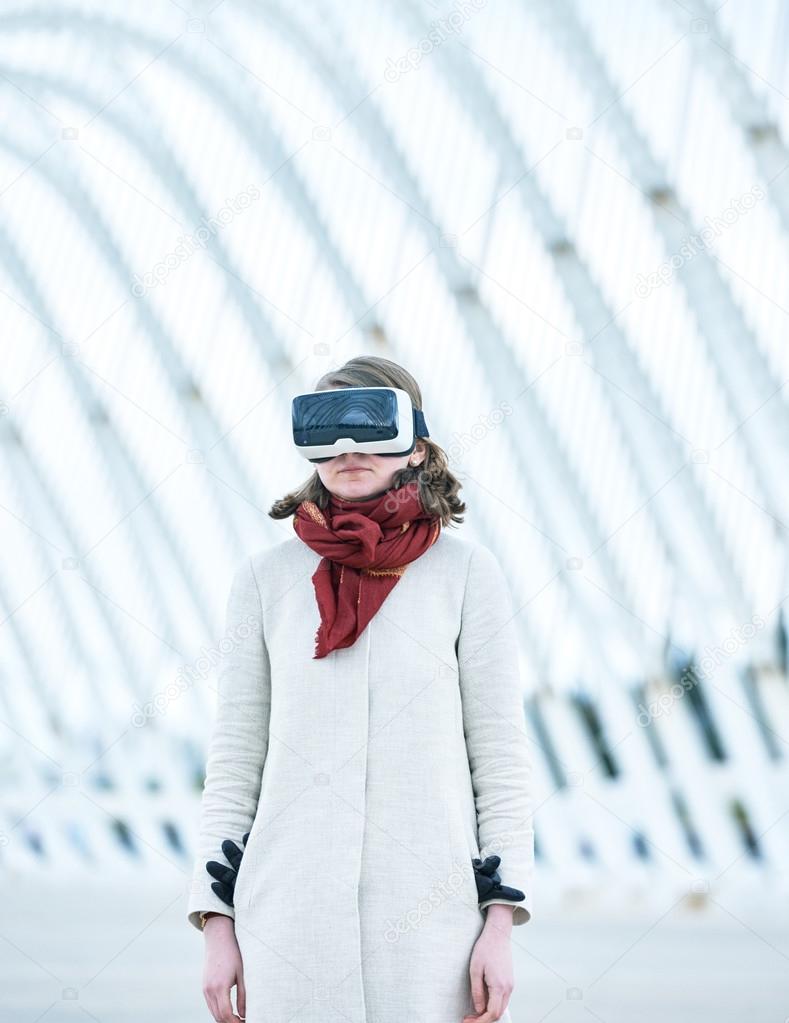 Woman wearing a virtual reality headset standing in futuristic b ...