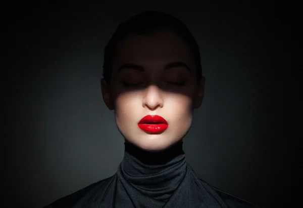 Beautiful model with bright red lips and face half covered in shadow ...
