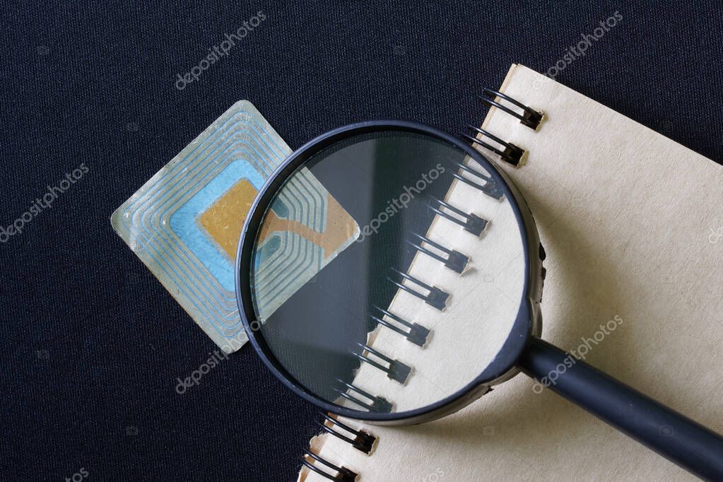 Transpondedor de etiquetas RFID bajo lupa, junto al bloc de notas ...