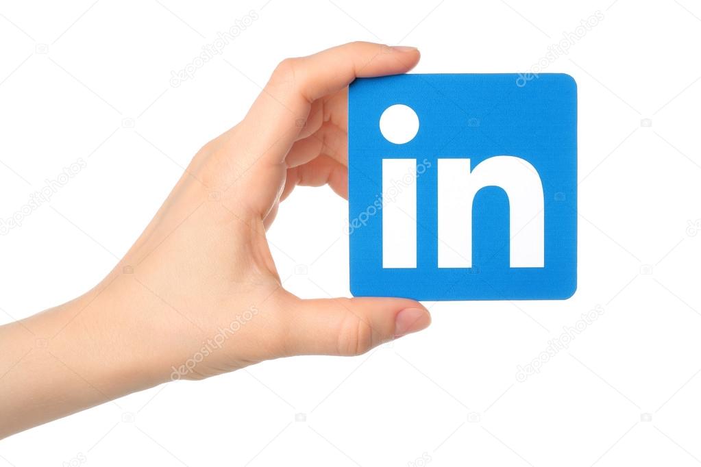 Hand holds Linkedin logo sign printed on paper on white background ...
