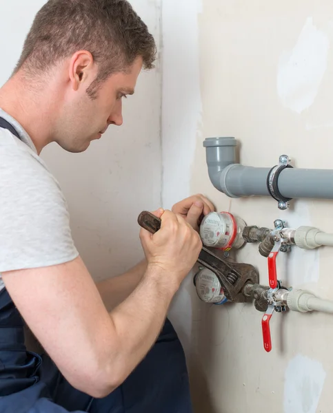 Male plumber fixing water meter with adjustable wrench. ⬇ Stock Photo ...