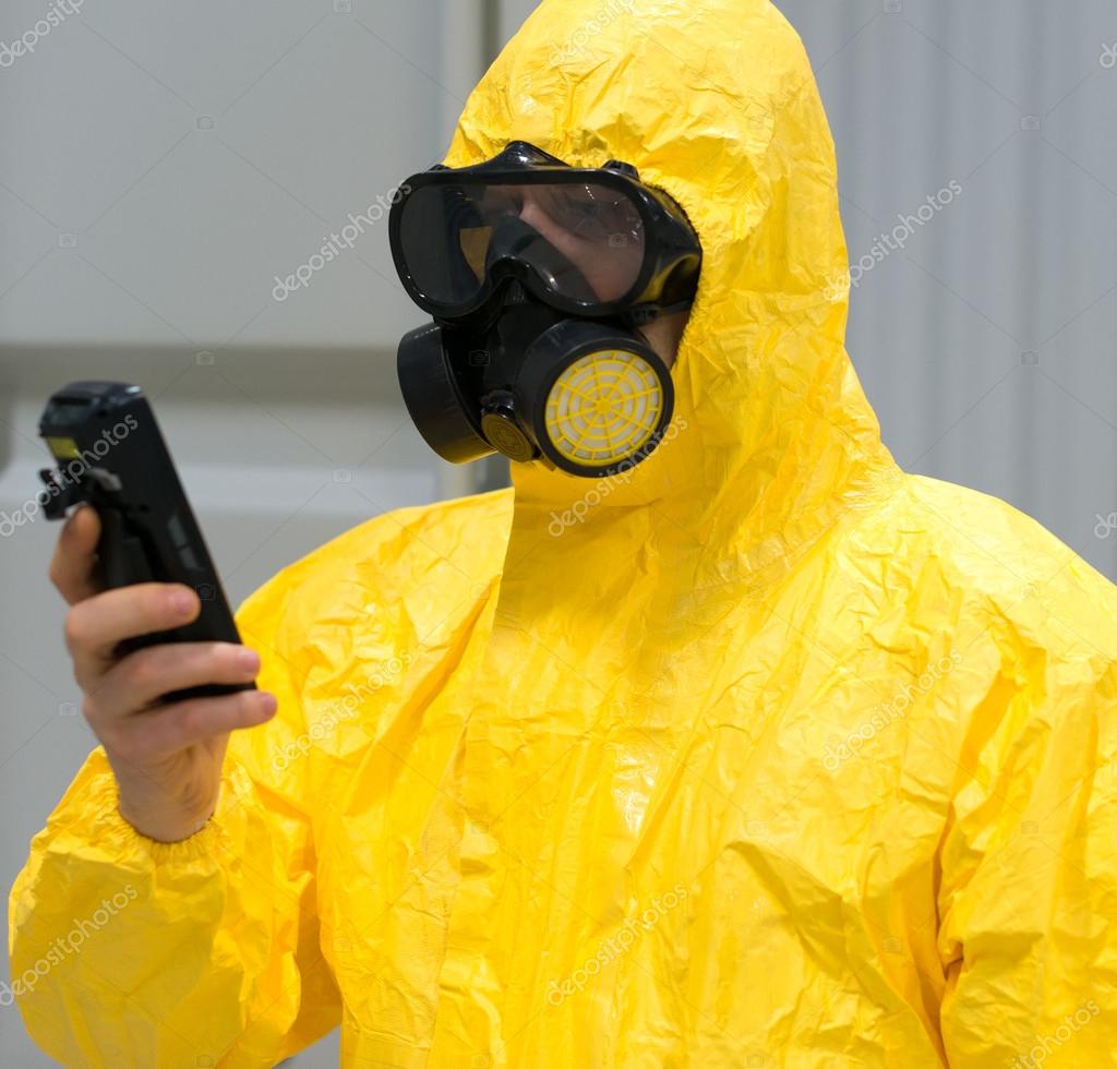 Worker in protective chemical suit checking radiation with geiger ...