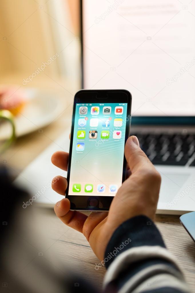 A man hand holding screen Apple app showing on iPhone 6 in office ...