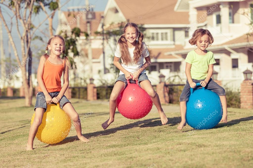 Happy kids playing with inflatable balls on the lawn Stock Photo by ...
