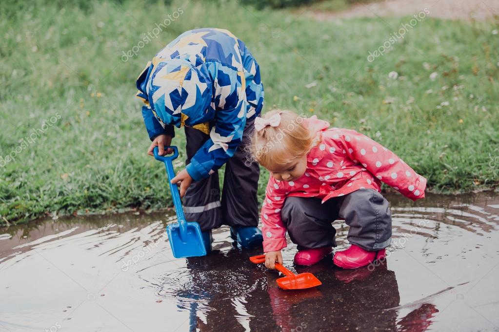 Little boy and girl playing in water puddle — Stock Photo ...