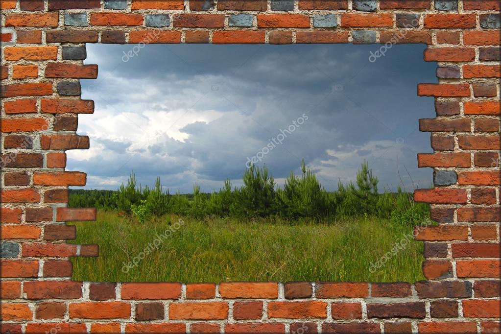 Muro de ladrillo roto y vista al campo con nubes de tormenta de truenos ...