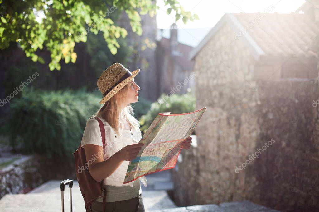 Chica viajero está utilizando el mapa de la ciudad en la calle de la ciudad. Turista mujer está ...