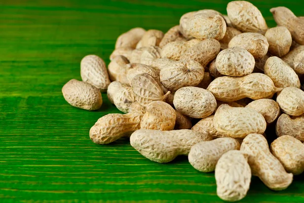 Peanuts in shell on a green board. Texture of nuts on a wooden old ...