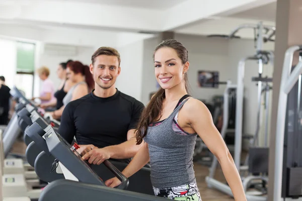 Happy coach assisting young woman in a gym - Stock Image - Everypixel
