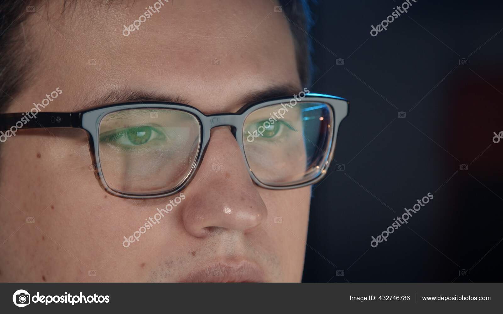Closeup of man working late at night looking at the screen of the ...